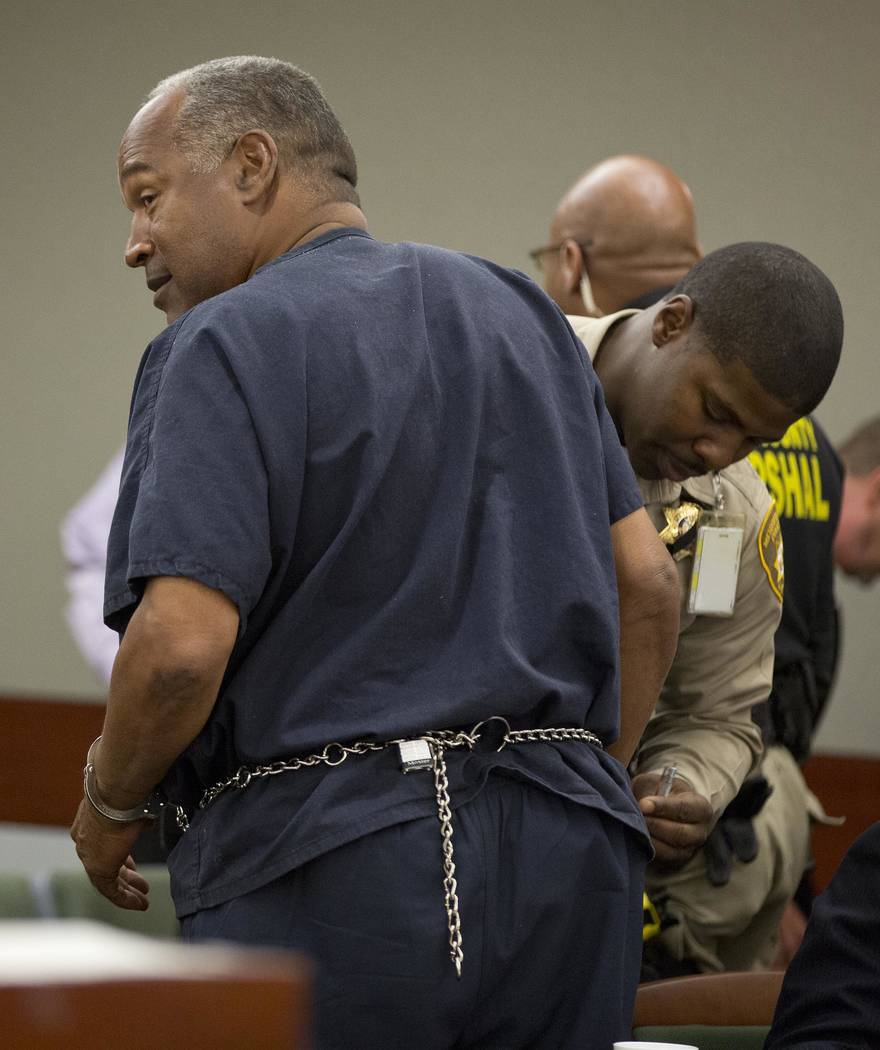 O.J. Simpson is handcuffed by Clark County corrections officer George ...